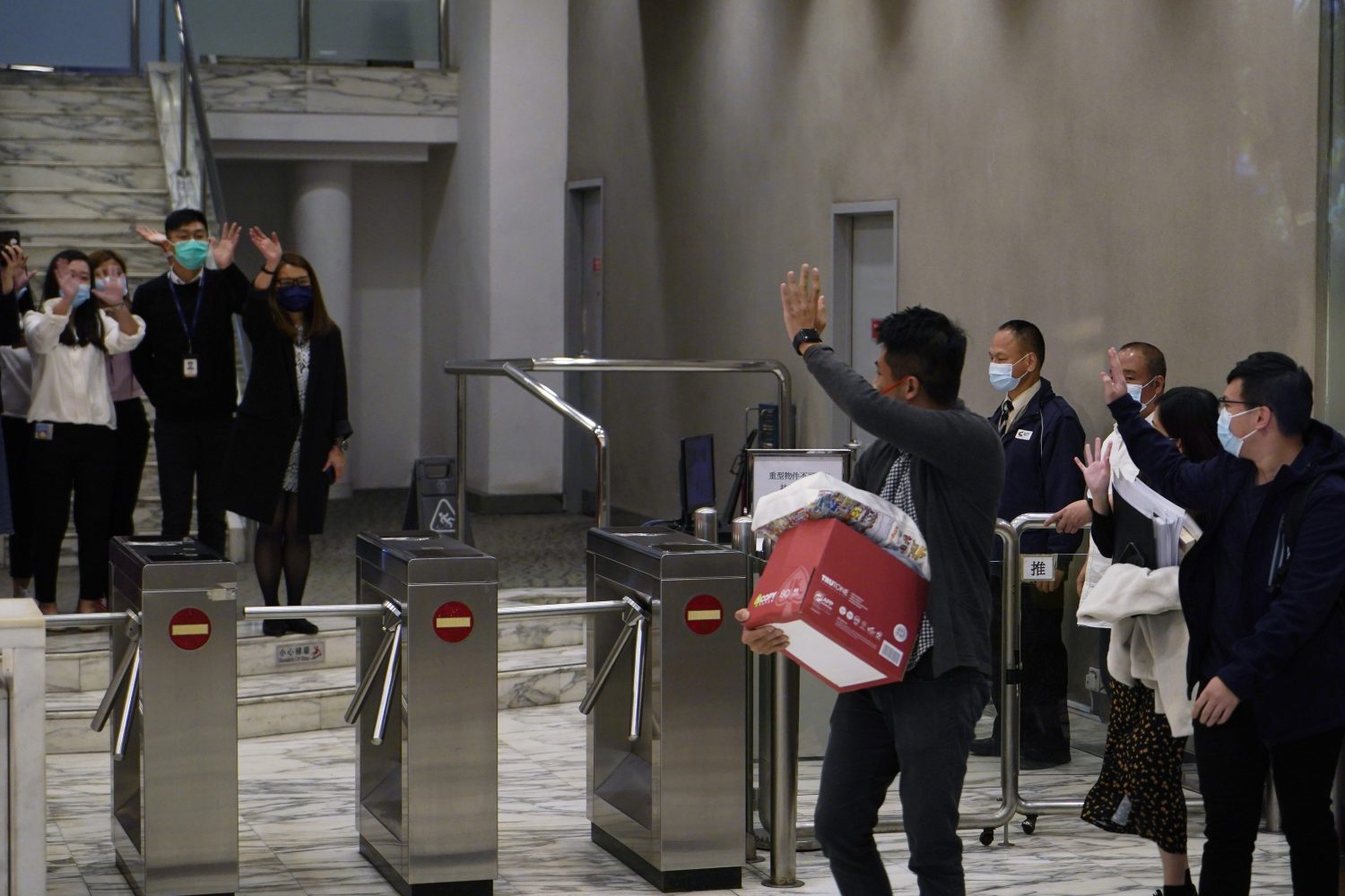 A journalist carries his belonging as colleagues wave to farewell in ...